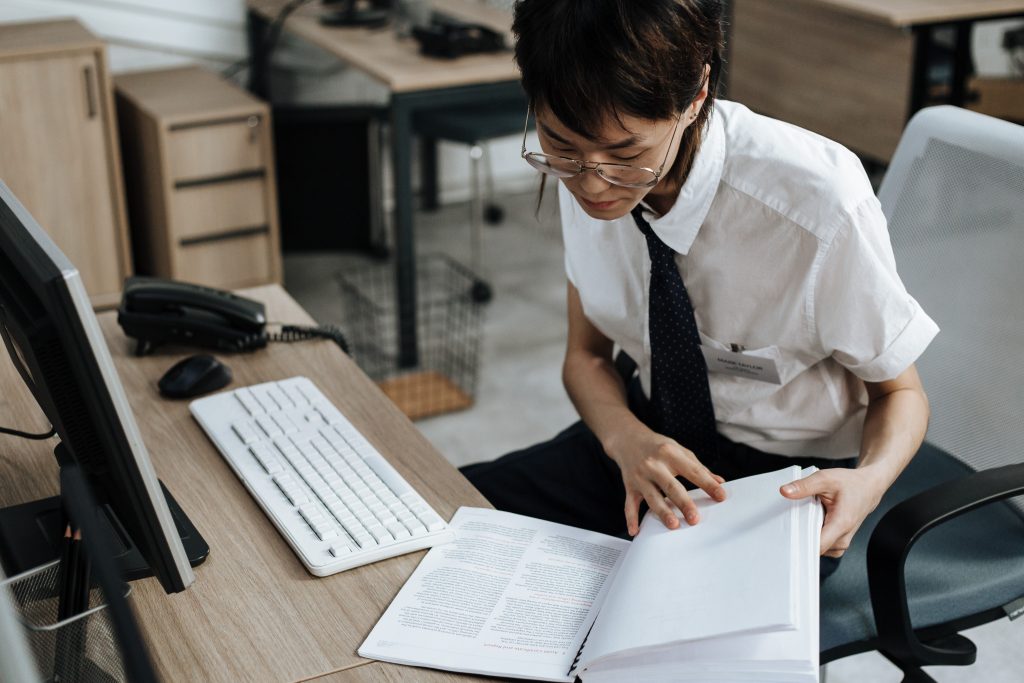 Student reading book infront of computer